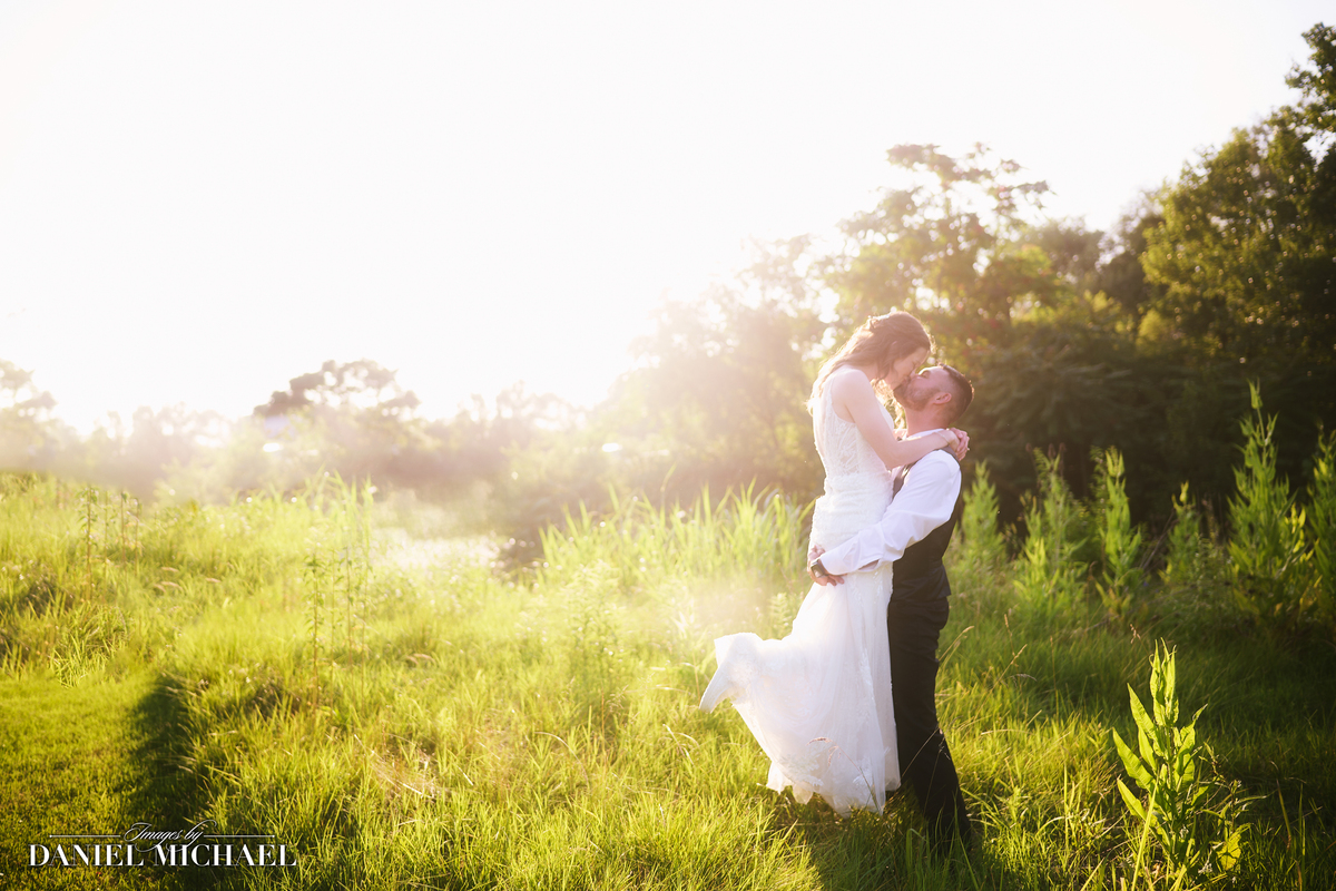 Light and Airy Wedding Photography of Groom Picking up Bride in field
